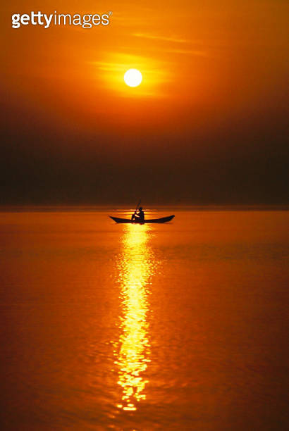 Beautiful Golden Sun over an African lake with fisherman and ...