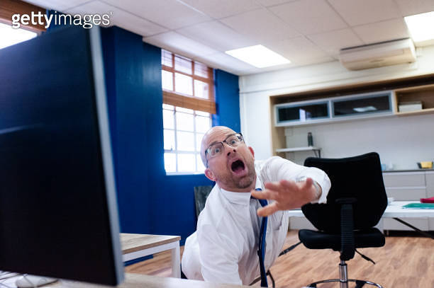 Male office employee standing looking at screen as his hand slips and ...