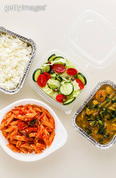 takeaway food in disposable containers: rice, vegetable curry, Italian ...