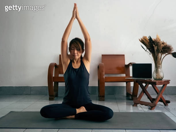 Woman wearing exercise suit,sitting on mat,press hands together and ...