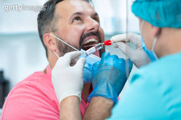 Patient holding face mask for doctor to take saliva sample with COVID ...
