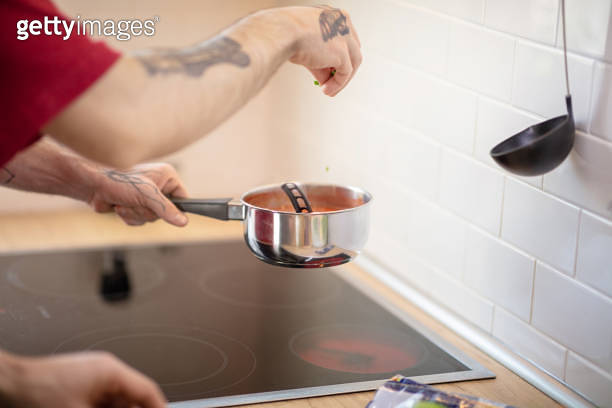Lifting pan with tomato sauce off the stove to add basil 이미지 ...