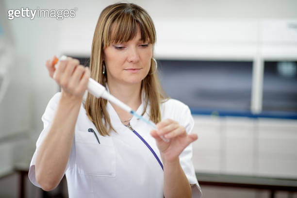 Female lab technician using pipette with samples (1266765604) - 게티이미지뱅크