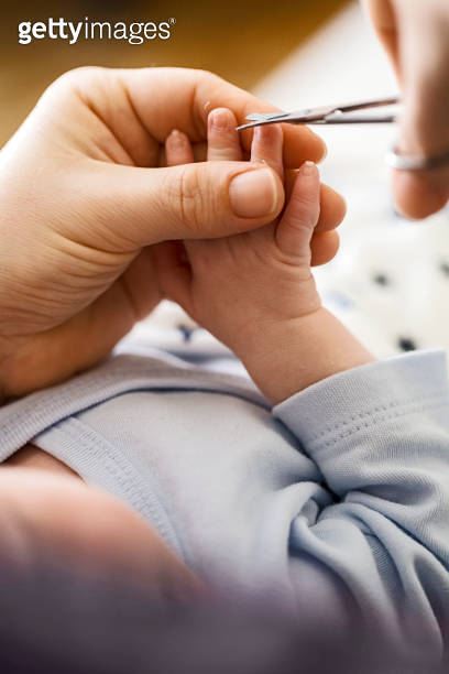 Mother holding baby's hand cutting nails 이미지 (1218166874) - 게티이미지뱅크