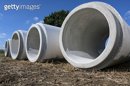 Large water pipes from concrete lying side by side on a construction ...