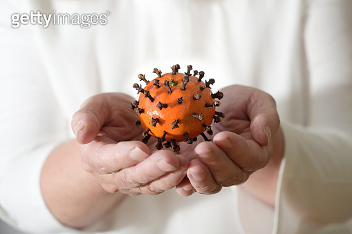 Hands are holding a tangerine with cloves, which looks like a ...