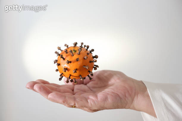 Hand under a tangerine with cloves, which looks like a coronavirus, but ...
