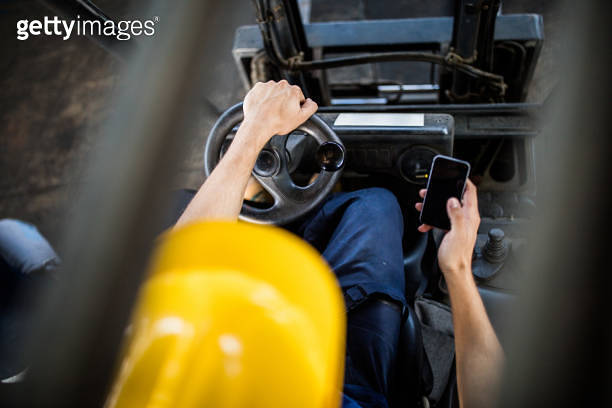 Above view of manual worker using cell phone in a forklift. 이미지 ...