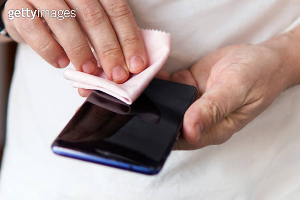 man rubs the screen of his black smartphone with a rag. Prevention of ...