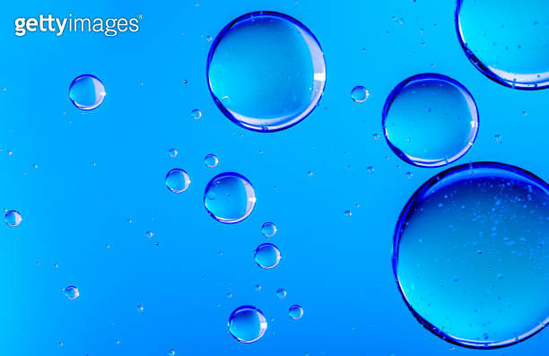 Blue oil drops in water. Bubbles of different sizes on blue abstract ...