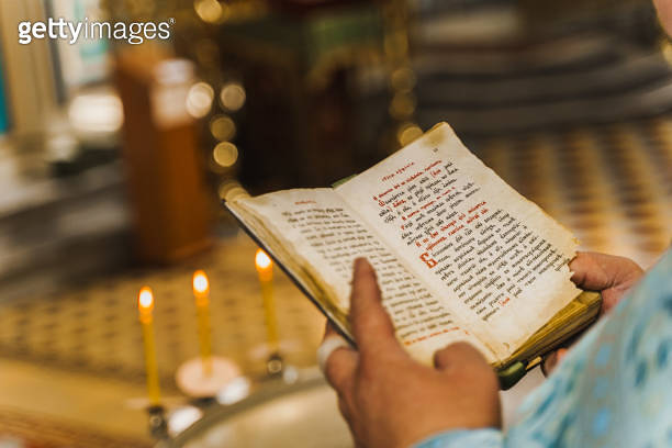 Holy book opened in priest hands in church. Priest reads pray. Orthodox ...