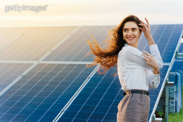 Model with solar panels stands in row on the ground at sunset. Girl ...
