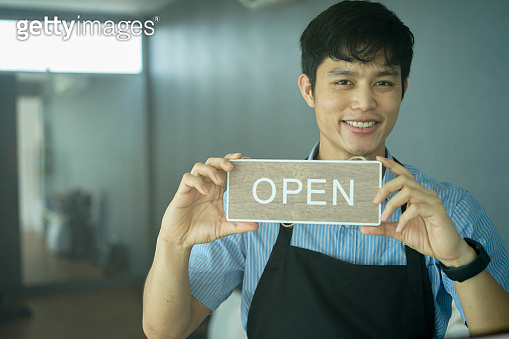 close up young business owner man holding open sign board to promote ...
