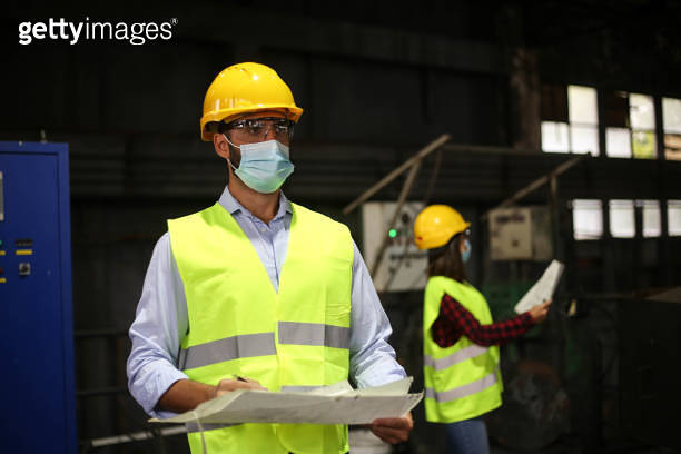 Factory workers work with face masks in the factory on a new project ...