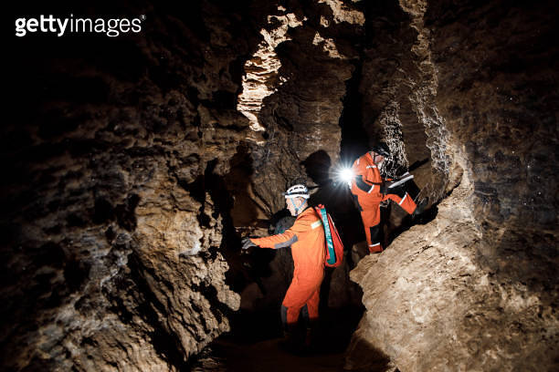 Two men, strong physique, explore the cave. Men dressed in special ...