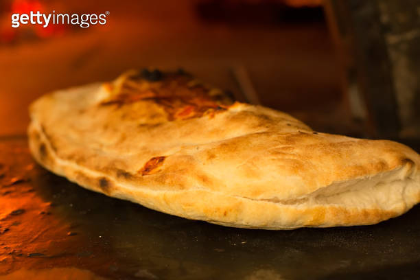 A baker's calzone pizza with a traditional Mediterranean wood-burning ...
