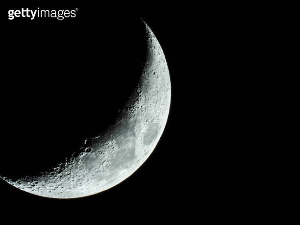 increasing sickle-shaped quarter moon with its moon craters stands in ...