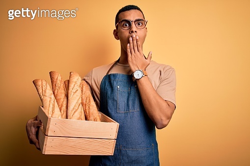 Young handsome african american bakery man holding wooden box with ...