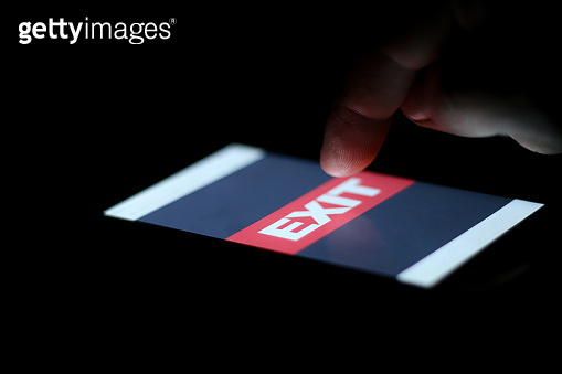 A finger touches the exit sign on the display of the phone. (1192455347 ...