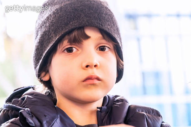 Serious pensive little boy looking at the camera wearing a toque hat ...