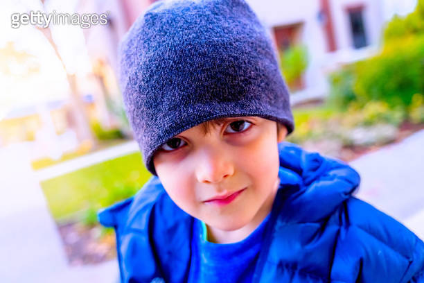 Smiling pensive little boy looking at the camera wearing a toque hat ...