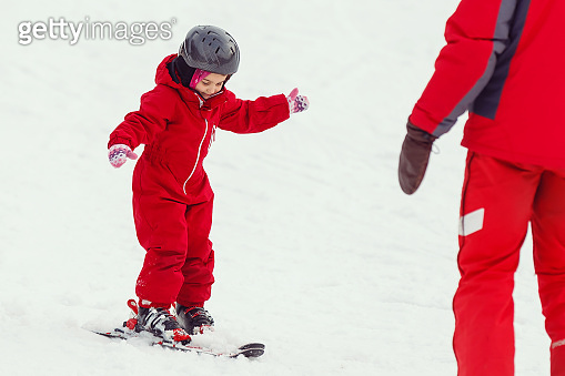 Girl child is learning to ski get up after a fall she slowly slides on ...
