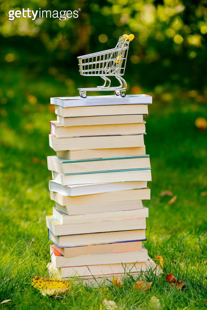 stack of books and shopping cart on the green grass in autumn 이미지 ...