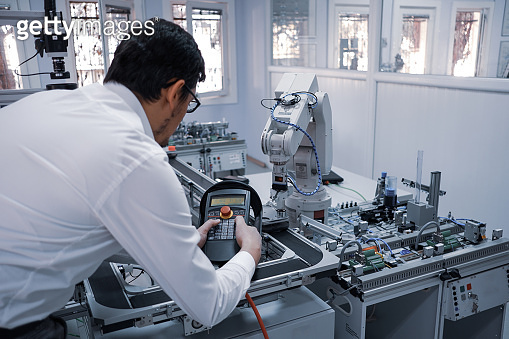 holding teach pendant to control a robot arm which is integrated on smart factory production ...