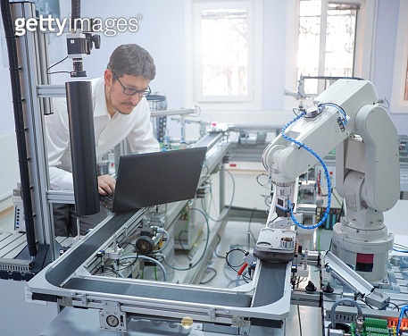 Industry 4.0 concept; Engineer is working on laptop to programming smart factory automation 이미지 ...