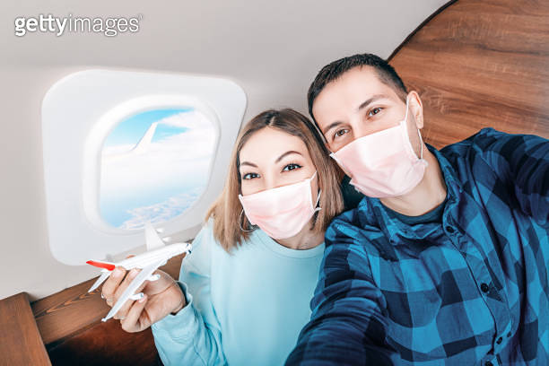 A couple of man and woman wearing medical masks and respirators travel ...