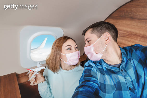 A couple of man and woman wearing medical masks and respirators travel ...
