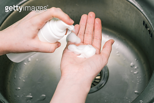 Putting whip foam soap bottle with foam on female hand. Lady using ...