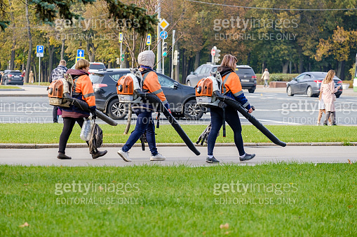 A group of utility workers walking down the street. On the backs of the ...