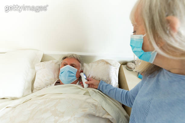 Sick senior man in bed with fever having temperature taken 이미지 ...