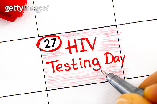 Woman fingers with pen writing reminder HIV Testing Day in calendar ...