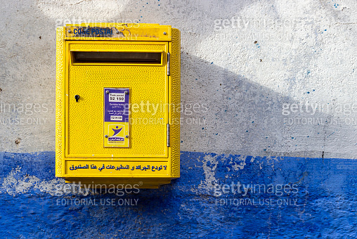 Yellow letter box on the blue wall. Typical house in the medina of ...