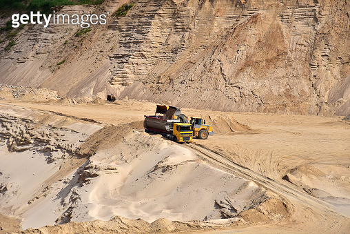 Wheel front-end loader loading sand into heavy dump truck at the ...