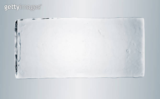 Large rectangle of clear ice with bubbles, against light grey ...