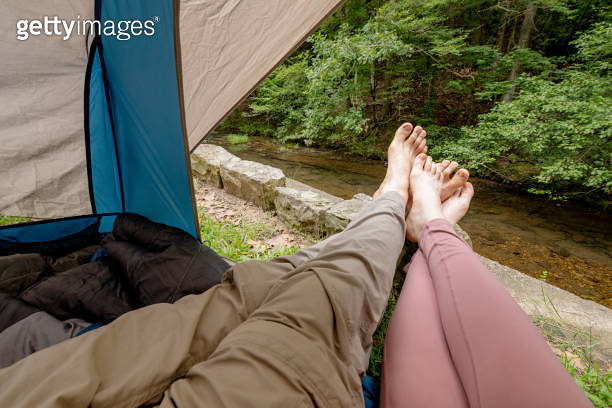 Camping Couples Legs Stretch Outside Tent on a Summer Day in Hot ...