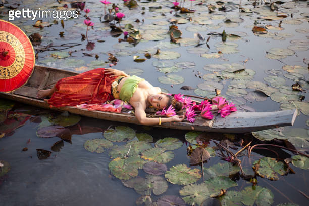 Portrait beautiful woman in local costume lying on the wooden boat with ...