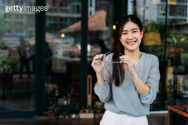 Young Asian woman taking off and showing a face shield at coffee shop ...