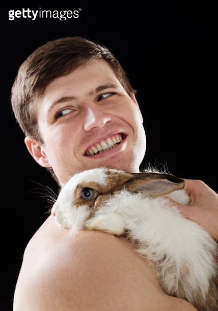 Handsome, smiling young man cuddles pet rabbit 이미지 (1210051396) - 게티이미지뱅크
