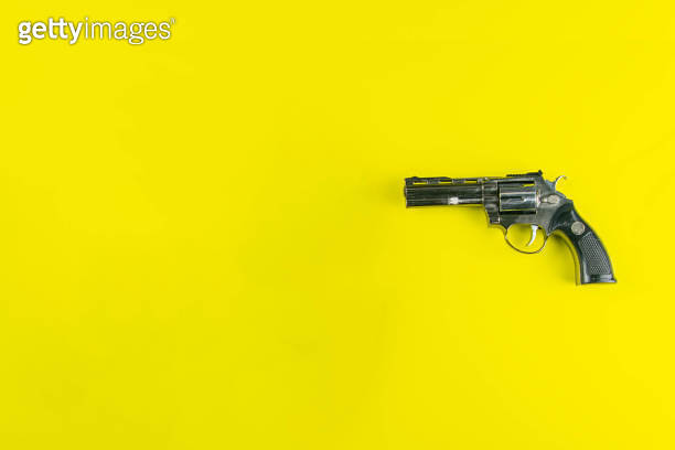Gun lying on the yellow background. Legalising of weapon. Crime concept ...