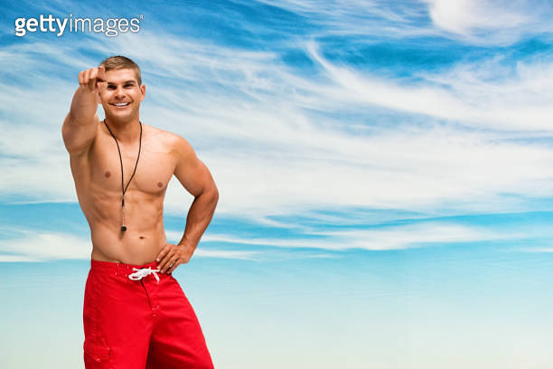 Young male lifeguard rescuing who is outdoors wearing shorts and ...