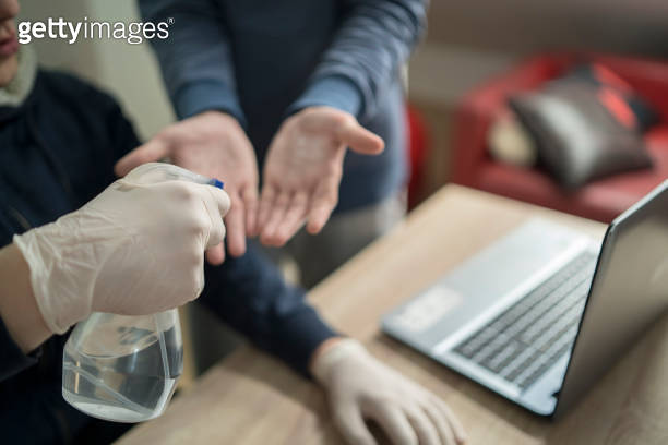 Colleagues at works disinfecting their hands before work to protect ...