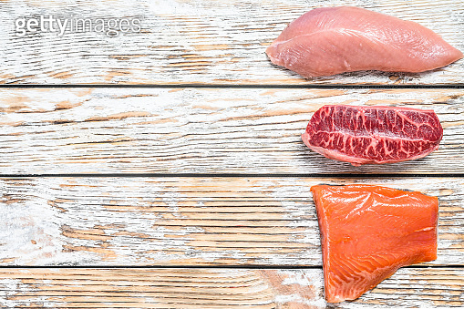 Three types of steaks on wooden table. Beef top blade, salmon fillet ...
