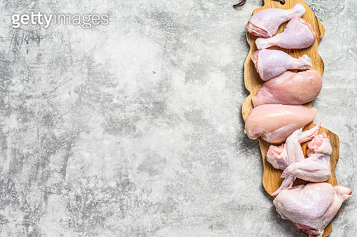 Raw uncooked chicken meat on a cutting board. Gray background. Top view ...