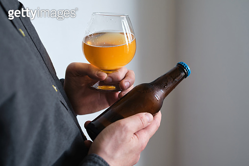A glass of beer and bottle in the hands of a man. Tasting brewed craft ...