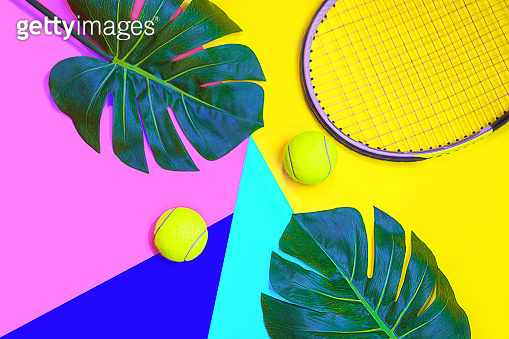 Tennis layout with tennis balls, racket and tropical monstera leaves on ...