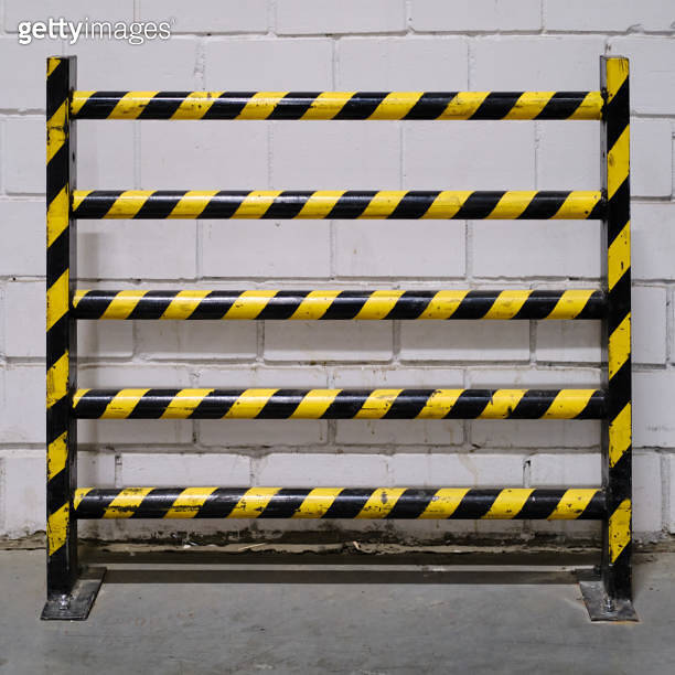A protective yellow-and-black barrier, near a dirty white wall. Concept ...